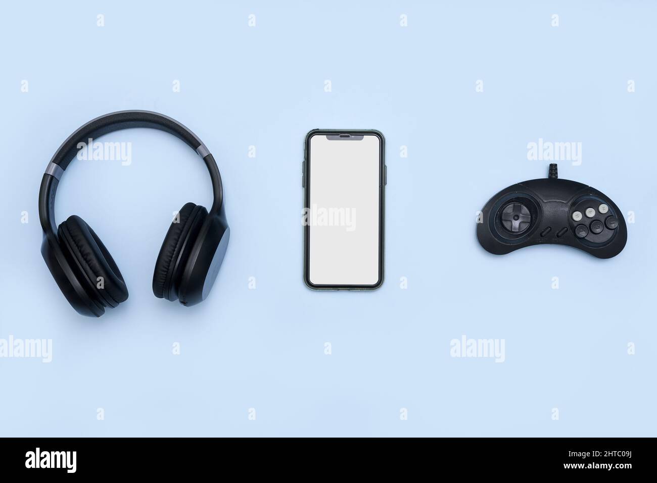 Top view shot of black headphones, a phone and a controller on a blue ...