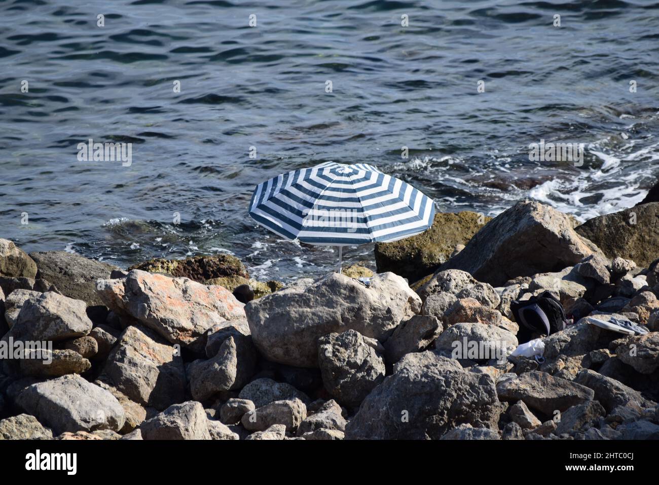Bright summer day outdoors with an umbrella stuck between rocks at the ...