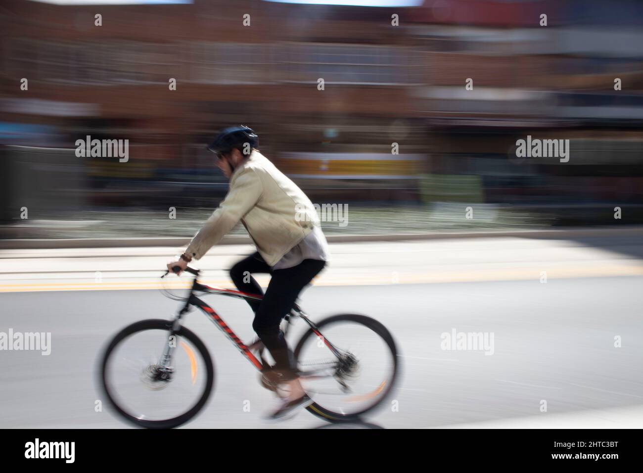 This dynamic image captures a cyclist in motion, pedaling quickly along ...