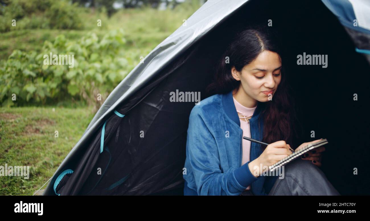 Woman sitting in the tent and writing on the notebook Stock Photo - Alamy