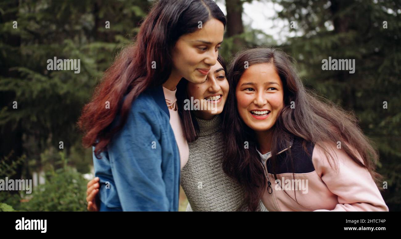 Young Indian girls with dark hair hugging each other in a pine forest ...