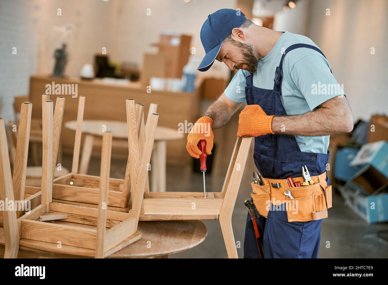 Bearded young man repairing chair in cafe Stock Photo - Alamy