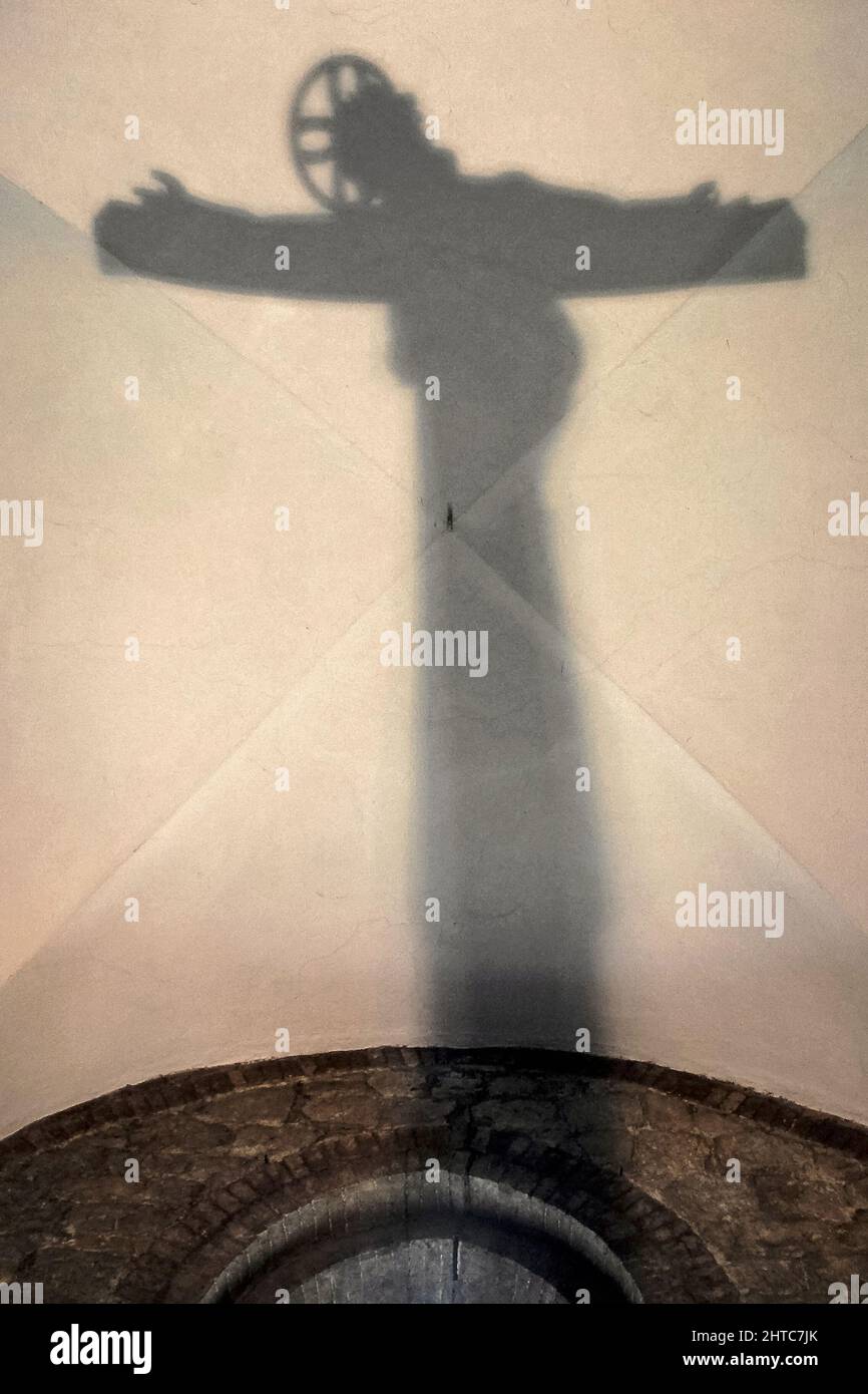 The grey shadow of a wooden crucifix is projected by fading daylight on ...
