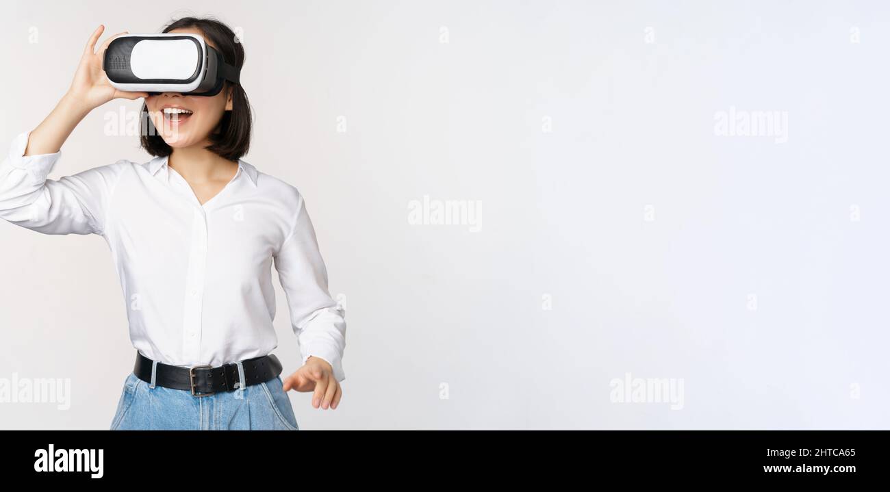 Excited young woman enter virtual reality in her glasses. Asian girl ...