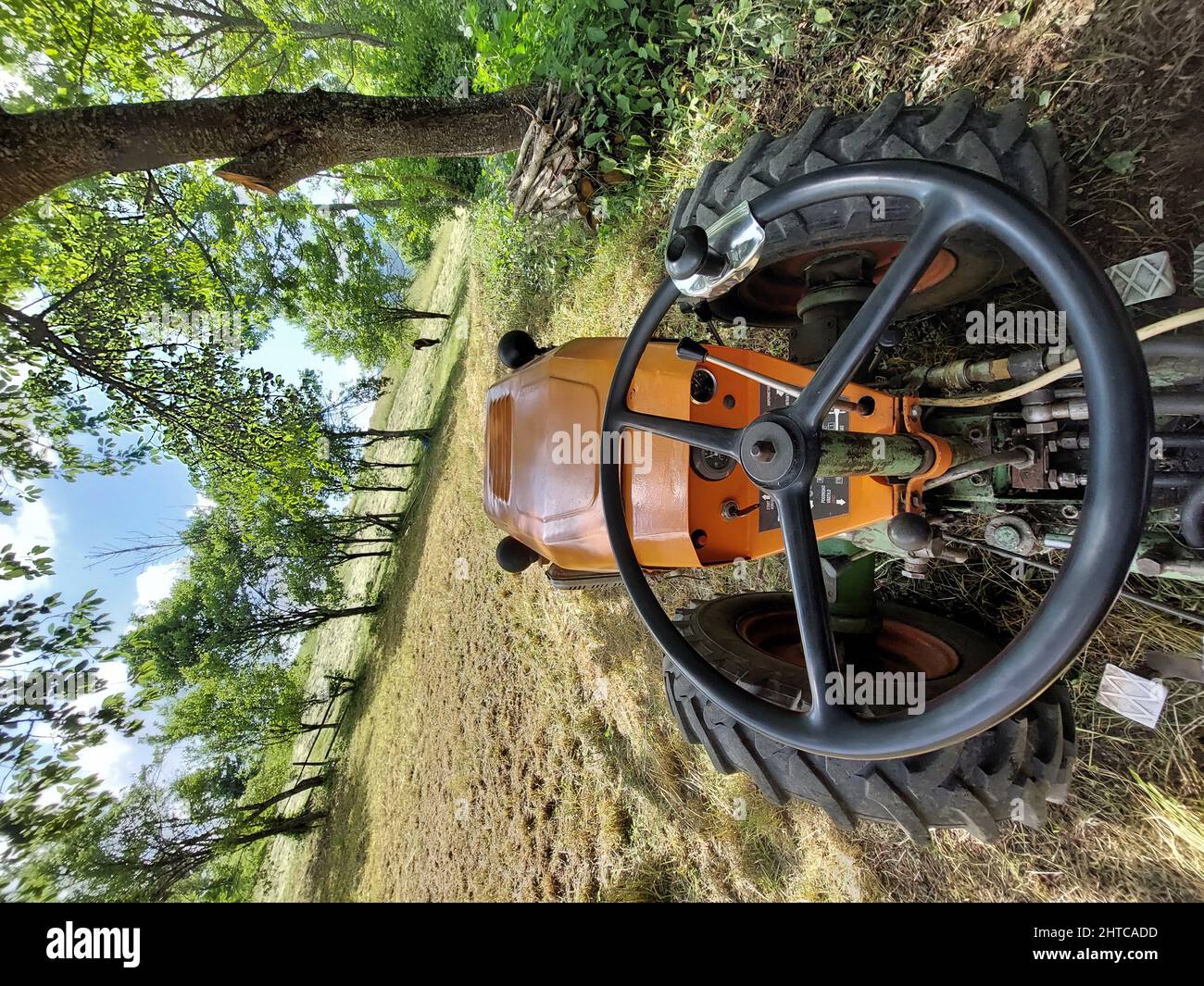 Vertical shot of an old tractor under trees on a sloppy farmland Stock ...