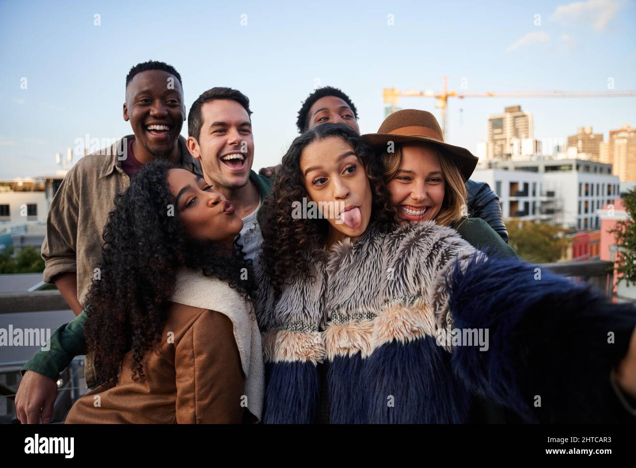 Cheerful multi-cultural group of friends taking a selfie on a rooftop ...