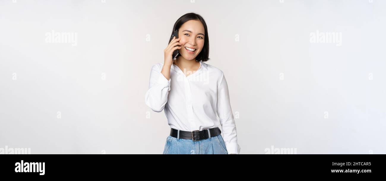 Friendly smiling asian woman talking on phone, girl on call, holding ...