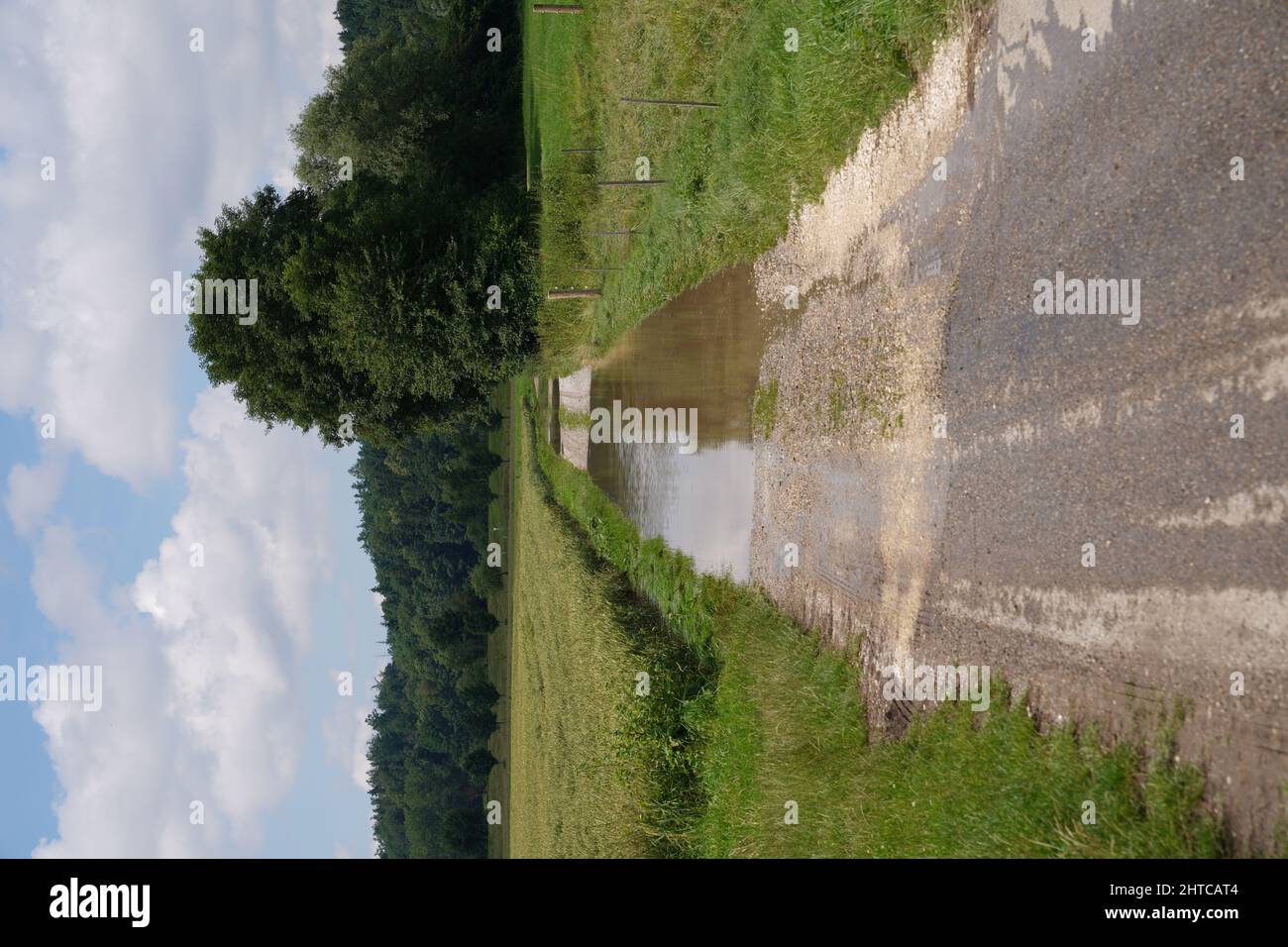 Beautiful shot of a wet pathway in a green field under the cloudy skies ...