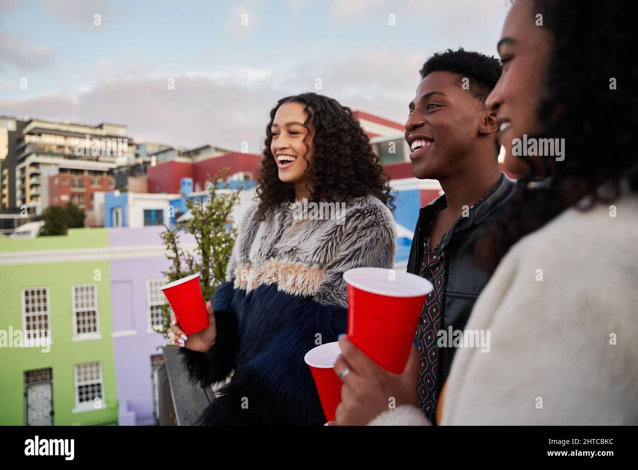 Group of multi-cultural young adults on a rooftop terrace looking at ...