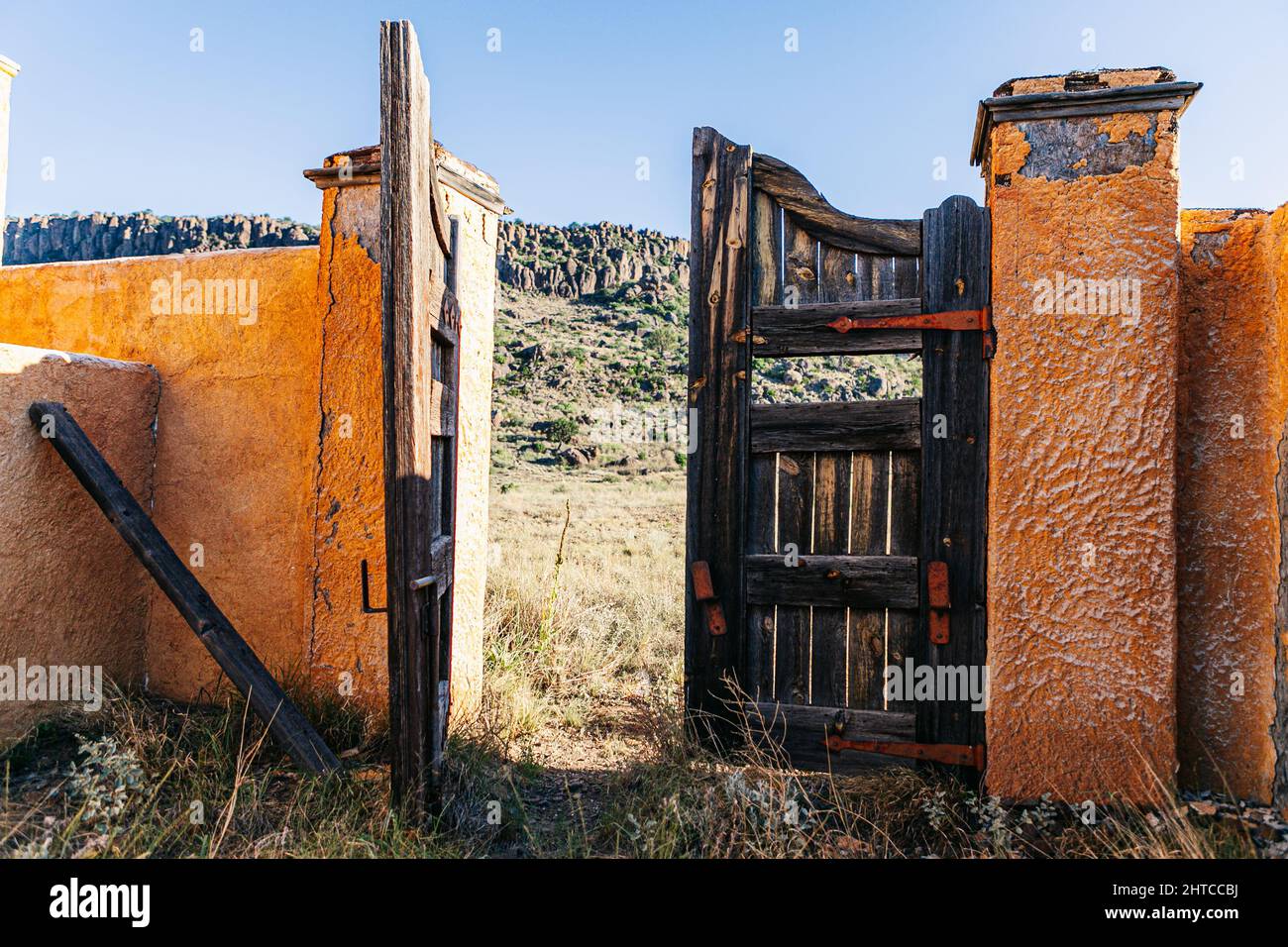 Weathered wooden gate dilapidated wall with tall grass blue sky Stock ...