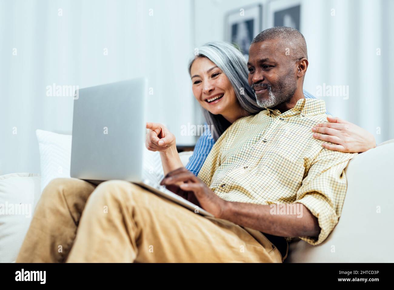 cinematic image of an happy multiethnic senior couple. Indoors ...