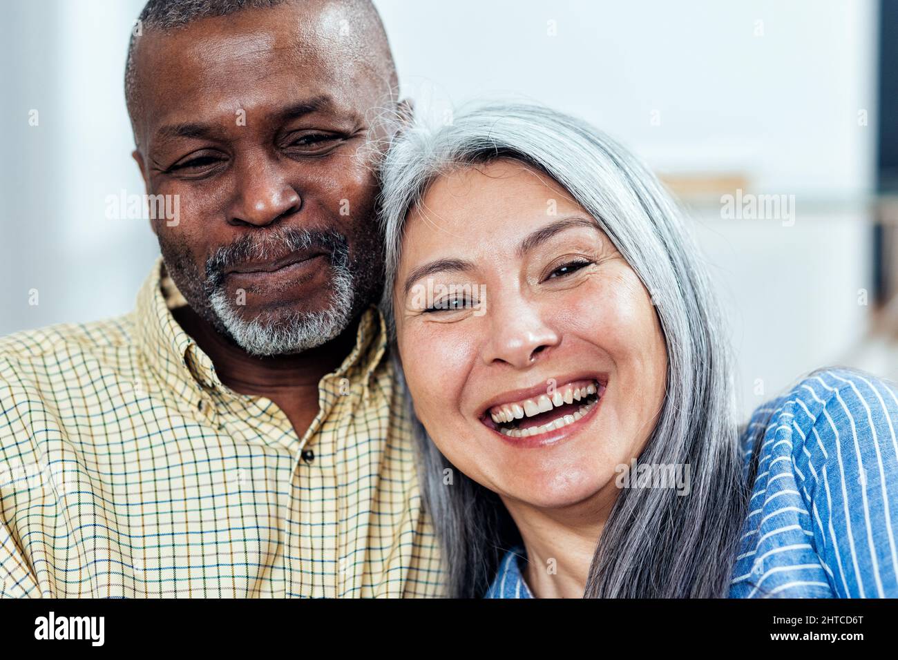 cinematic image of an happy multiethnic senior couple. Indoors ...
