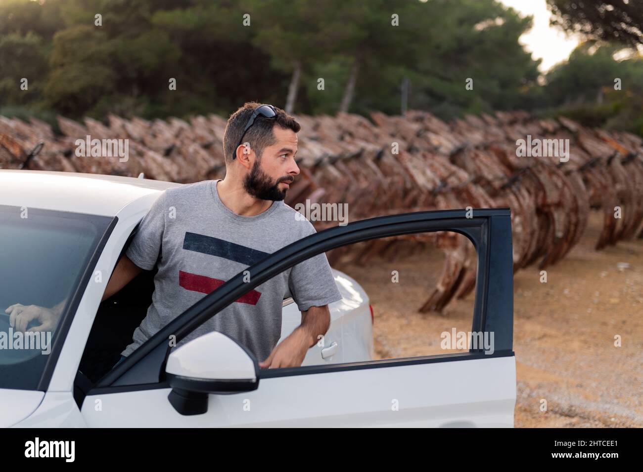 attractive bearded young man getting out of his car door, road trip and ...