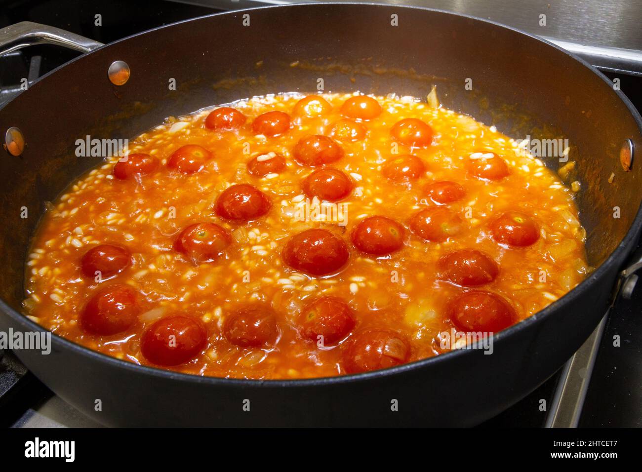Cherry tomato risotto cooking Stock Photo - Alamy