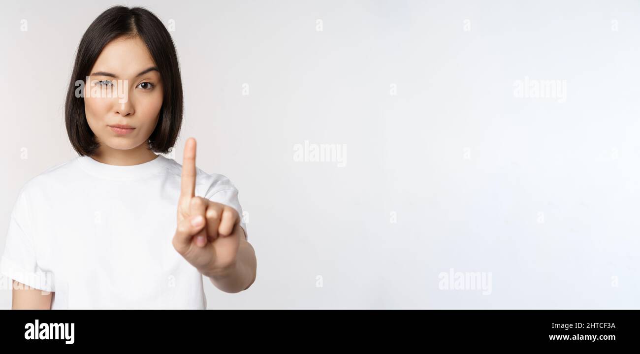 Image of asian girl showing stop, prohibit smth, extend one arm to show forbidding, taboo ...