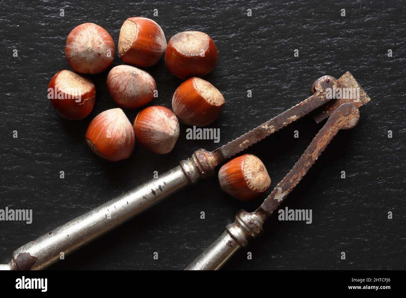 Shot of a very old nutcracker and hazelnuts on a slate for food ...