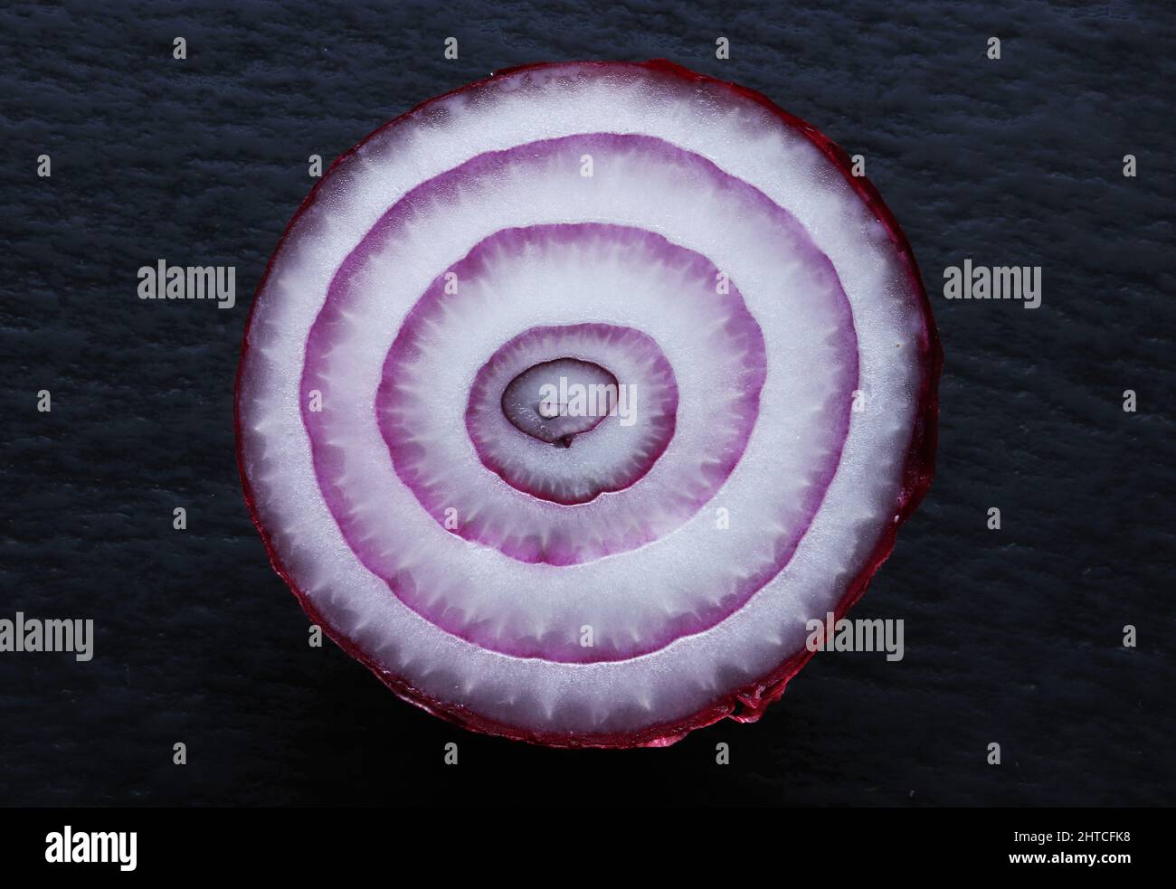 Shot of a red onion cut in half on slate background Stock Photo - Alamy