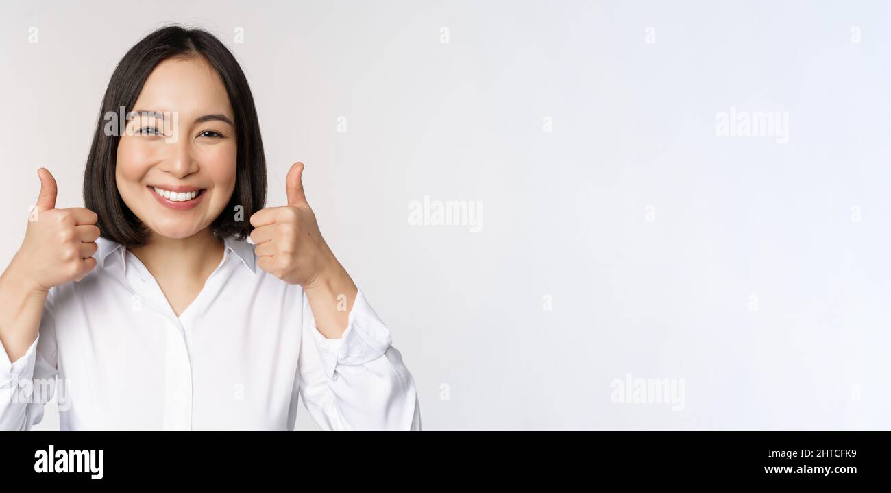 Cheerful asian woman face, showing thumbs up and smiling, pleased by ...