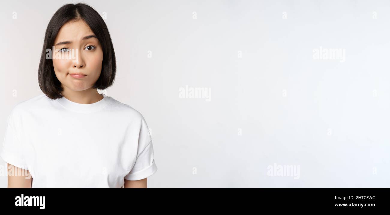 Image of young asian brunette woman in white t-shirt, smirk and look ...