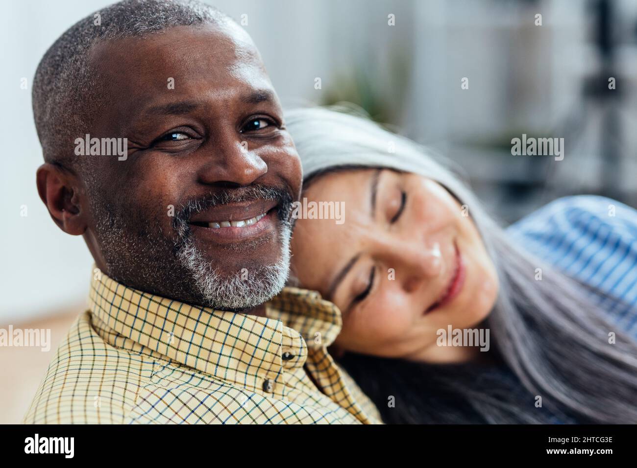 cinematic image of an happy multiethnic senior couple. Indoors ...