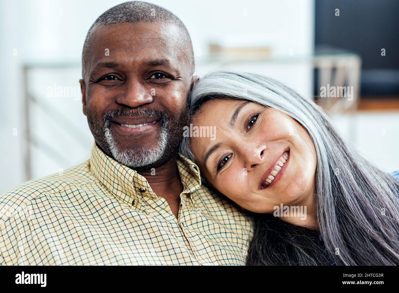 cinematic image of an happy multiethnic senior couple. Indoors ...