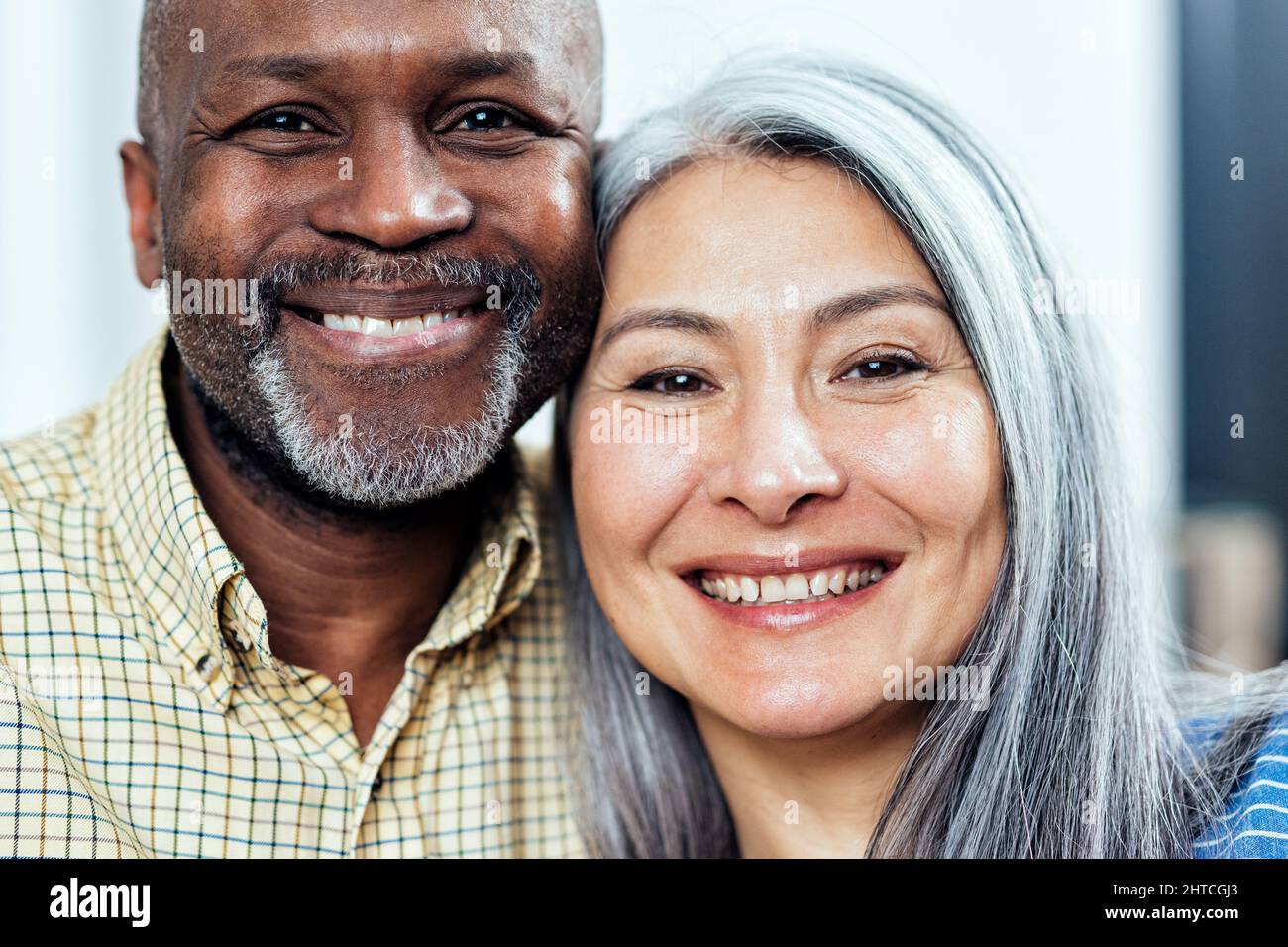 cinematic image of an happy multiethnic senior couple. Indoors ...