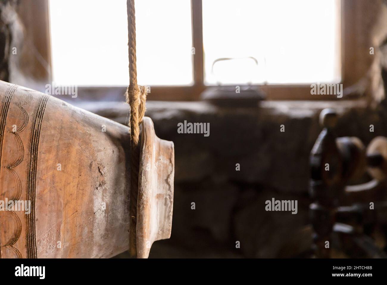 Closeup of a clay butter churn with a window and a stone wall on a ...