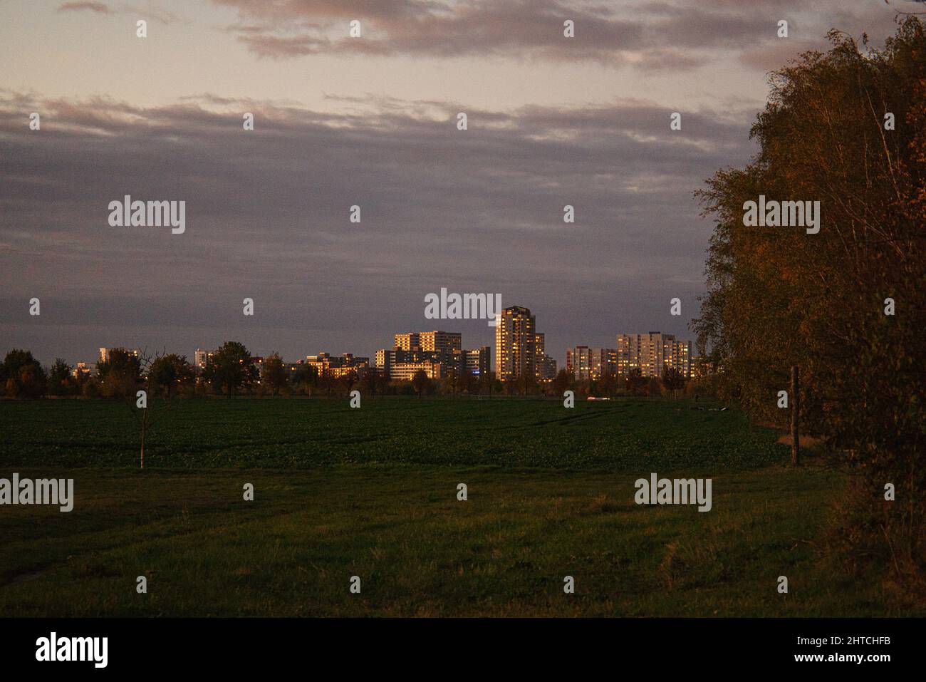 Beautiful scenery of the cityscape and the green fields during sunset ...