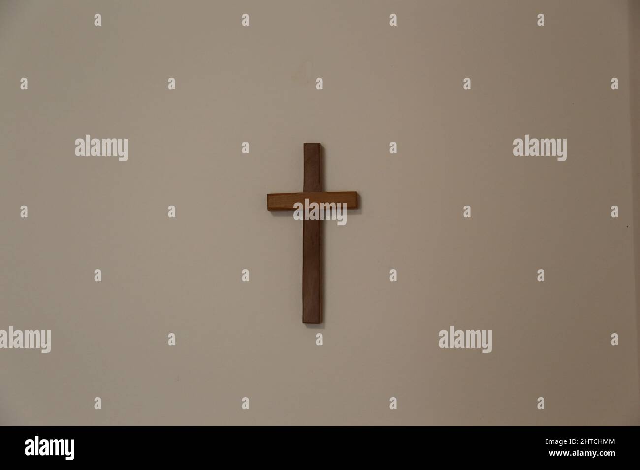 Wooden simple cross on a white wall in the room Stock Photo - Alamy