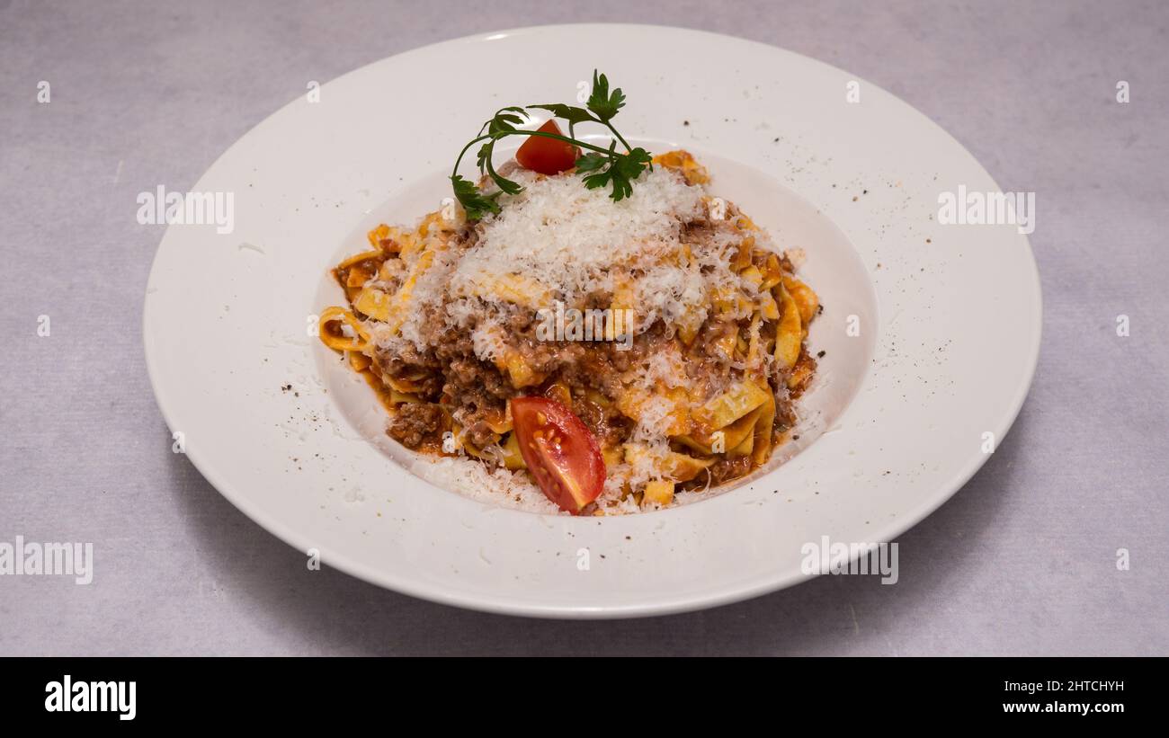 Closeup shot of a lasagna dish with fresh herand tomatoes on a white ...
