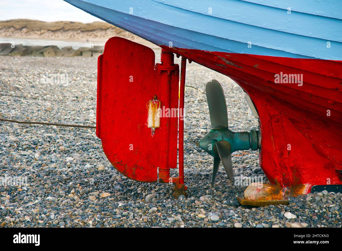 Closeup of the ship propeller and rudder standing on a rocky beach ...