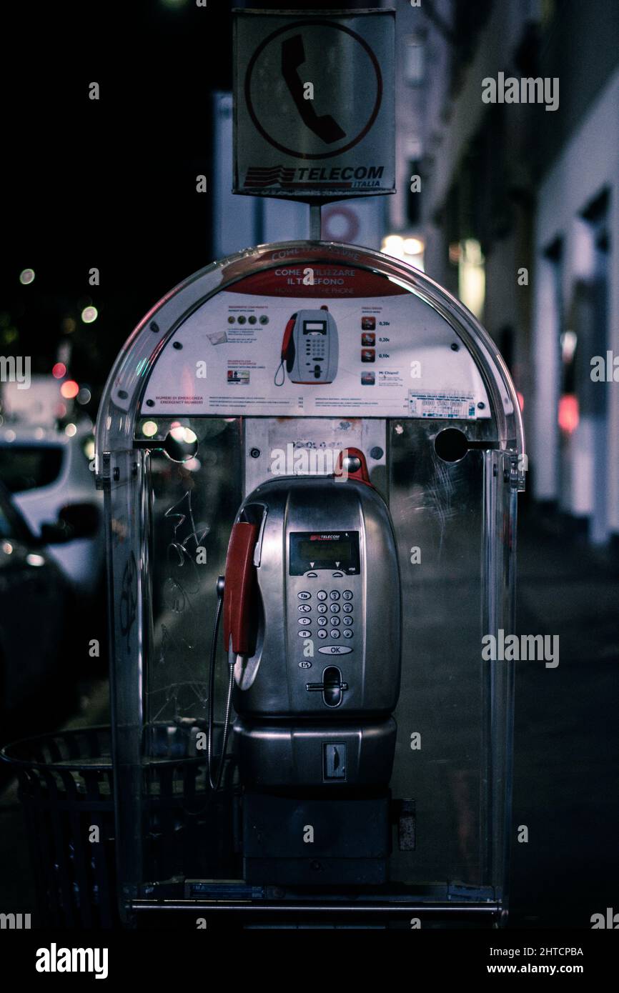 Vertical shot of a public telephone on the pavement of Piazza 25 Aprile ...