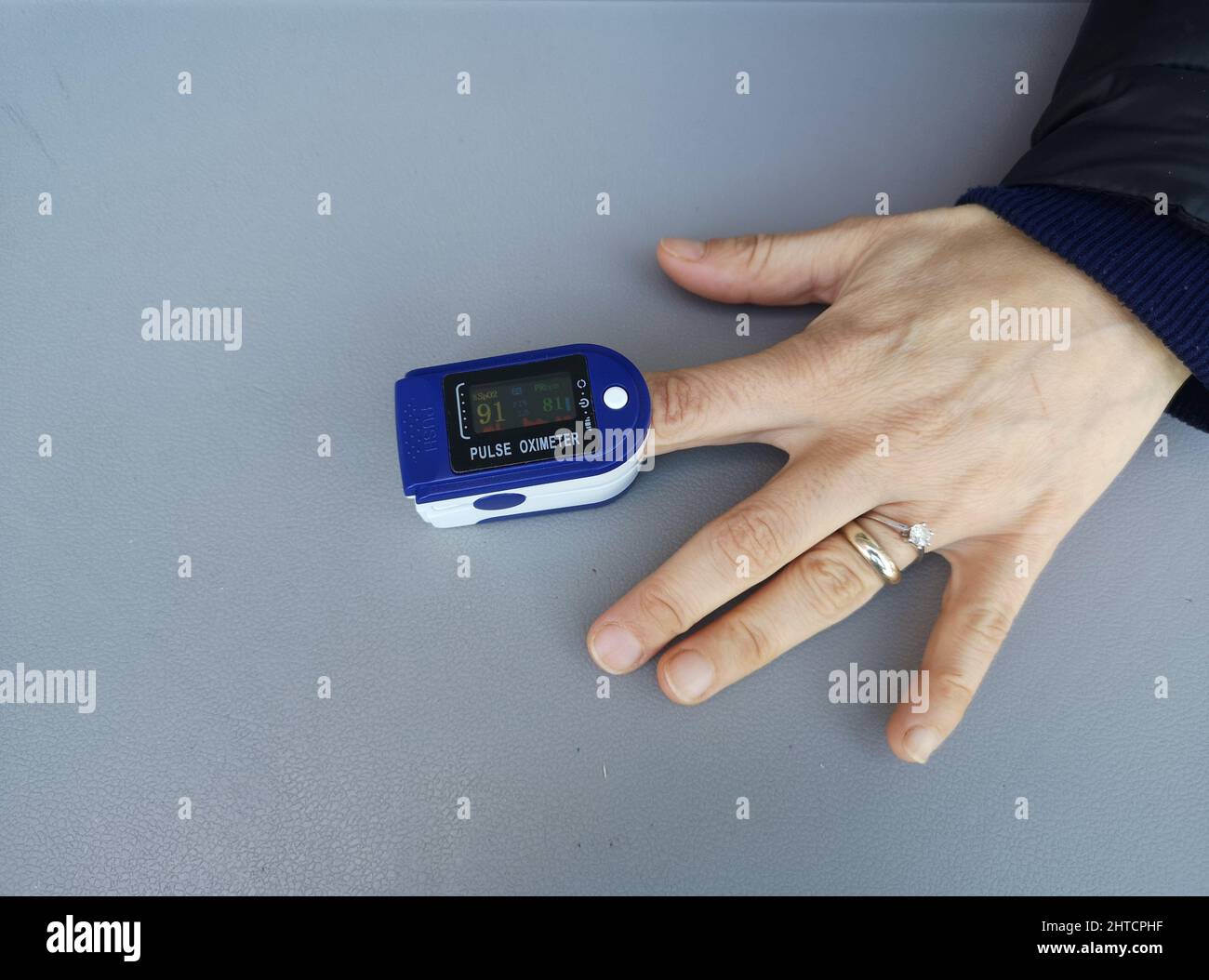 Person monitoring the oxygen saturation of the blood with an oximeter ...