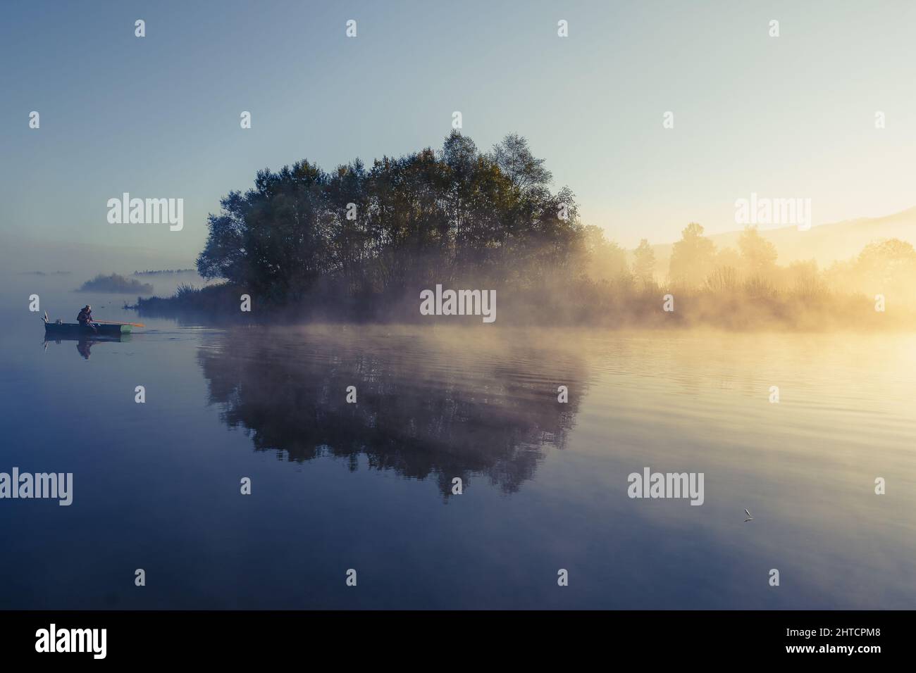 Fisherman on a boat on the Forggensee covered in the fog during the ...
