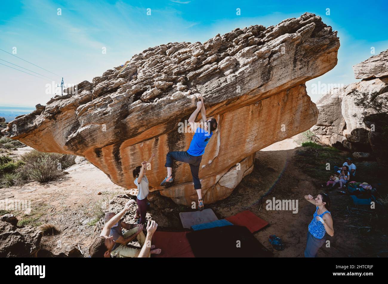 Group of people supporting a man climbing a rock Stock Photo - Alamy