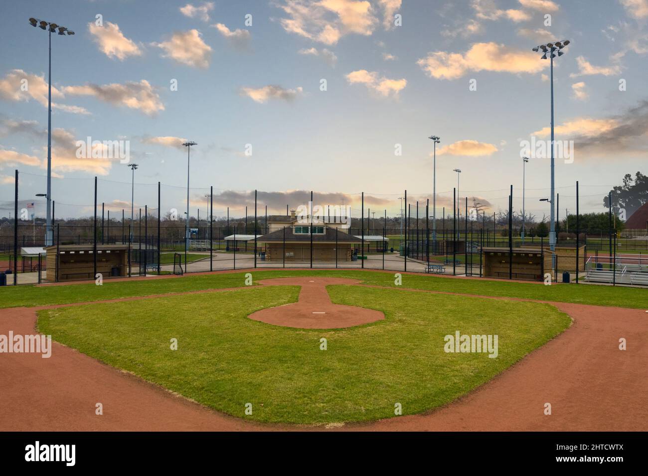 Panoramic shot of a baseball field surrounded by a net fence with ...