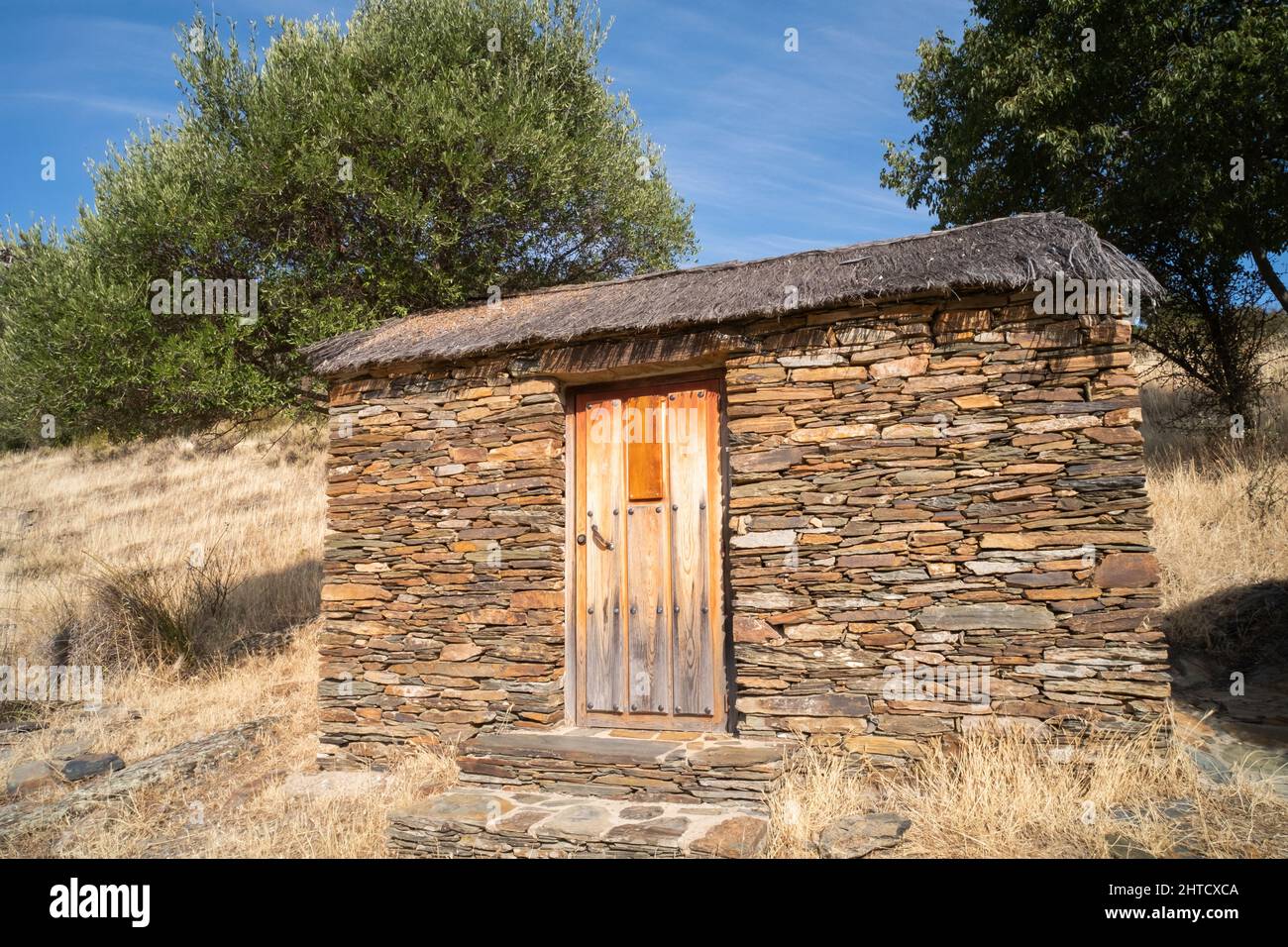 Old square-shaped cabin or hut with slate stone walls and a broom and ...