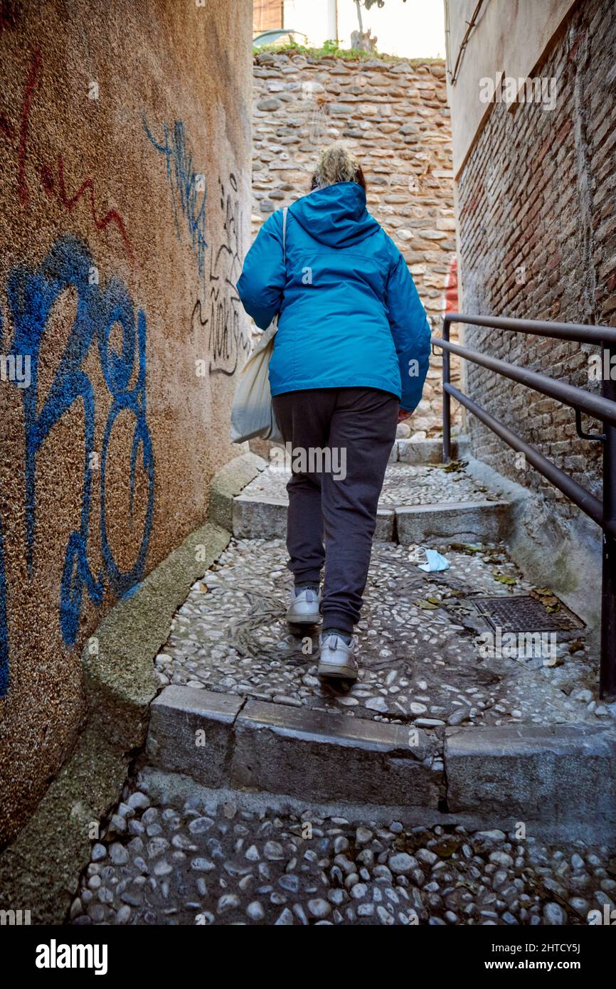 Vertical back view of a young Caucasian girl climbing up the stairs in ...