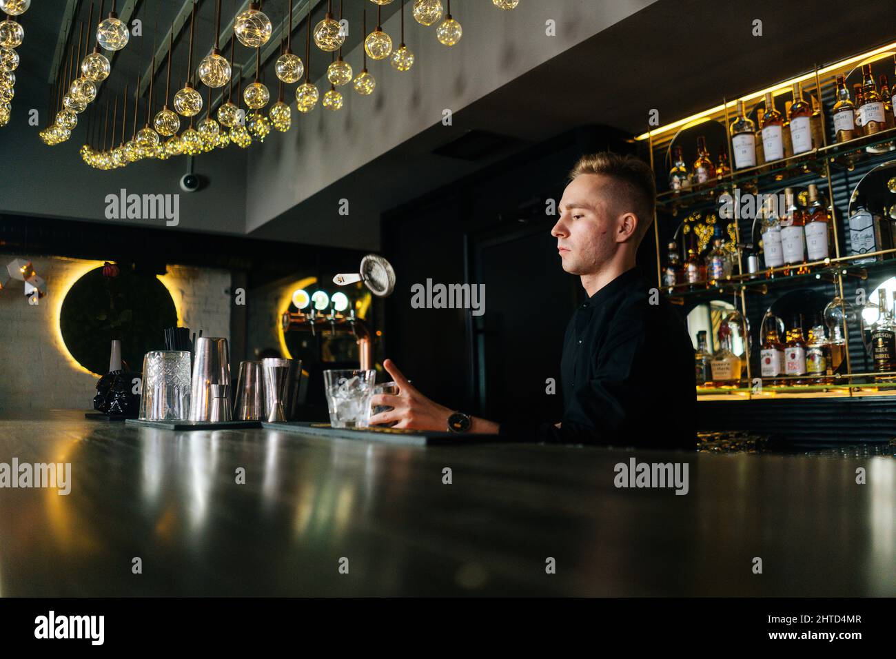 Low-angle view of serious bartender making refreshing alcoholic ...