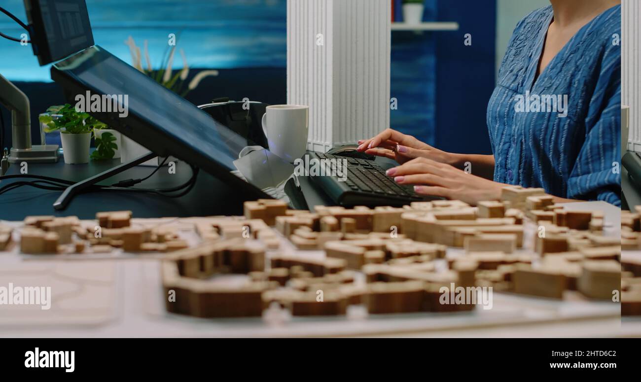 Close Up Of Hands Using Touch Screen Monitor With Building Model And Maquette On Table