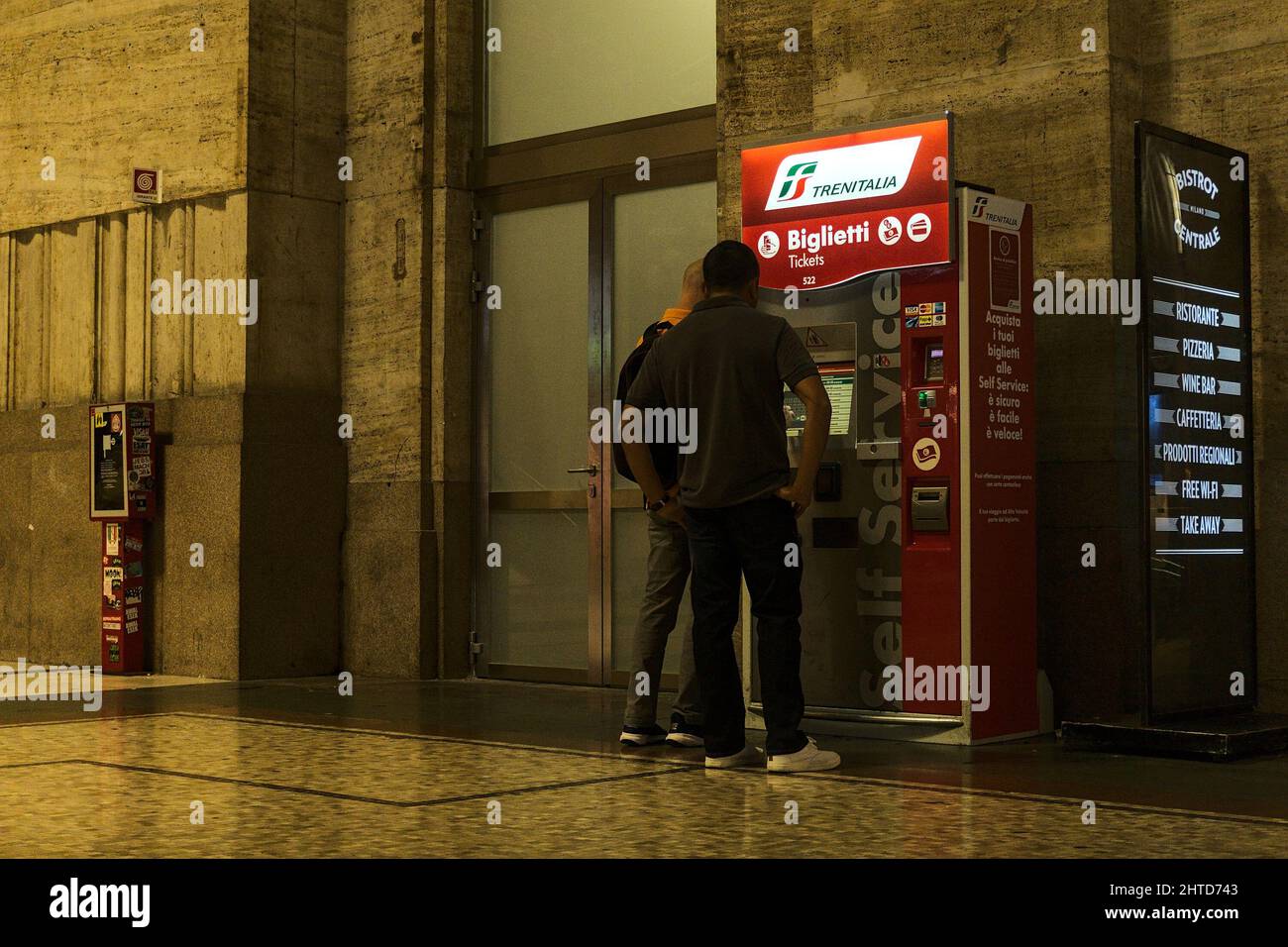 A shot of two boys buying a ticket from a train self ticket machine at ...