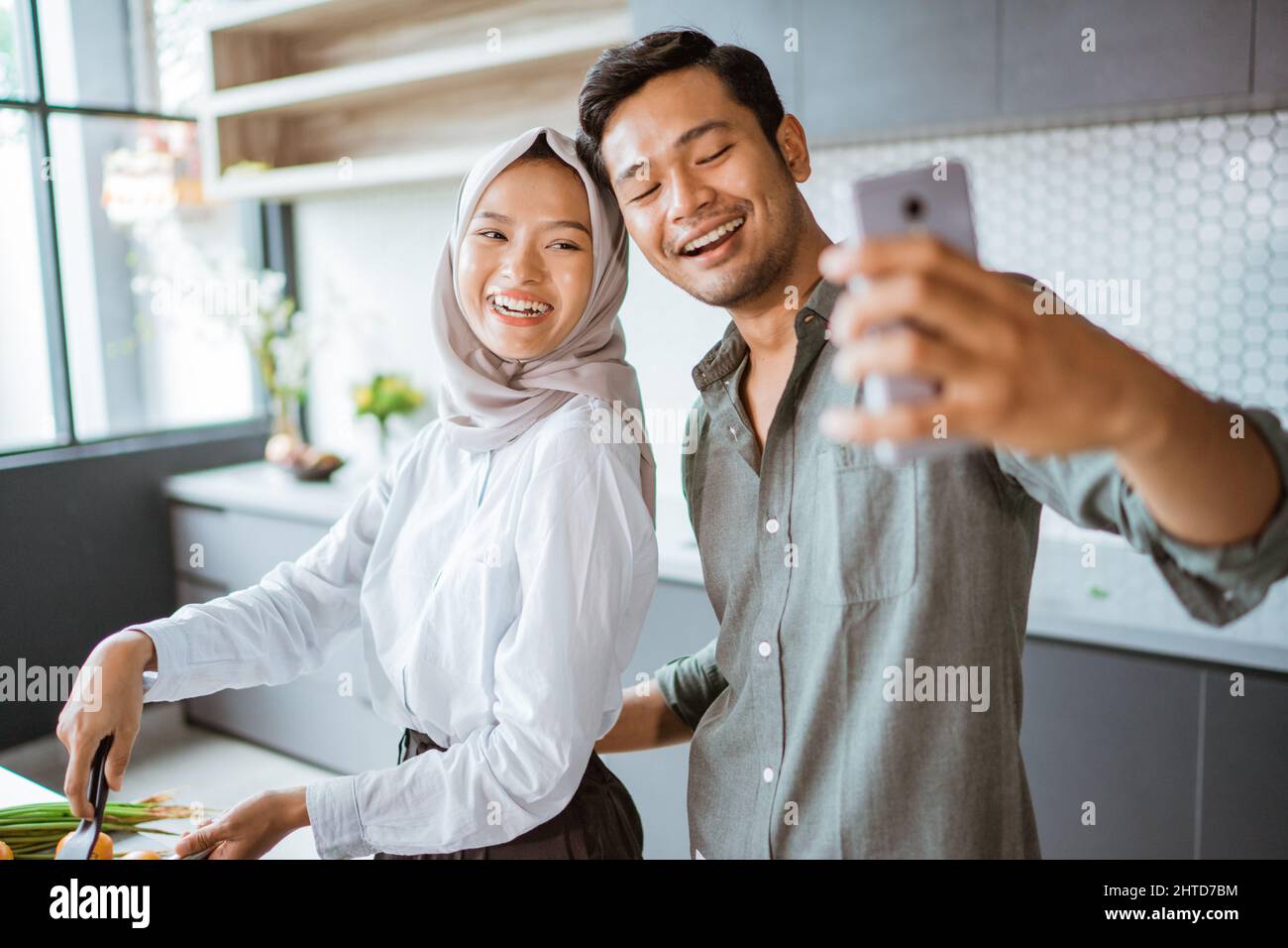 muslim couple cooking their food in the kitchen and taking selfie Stock ...