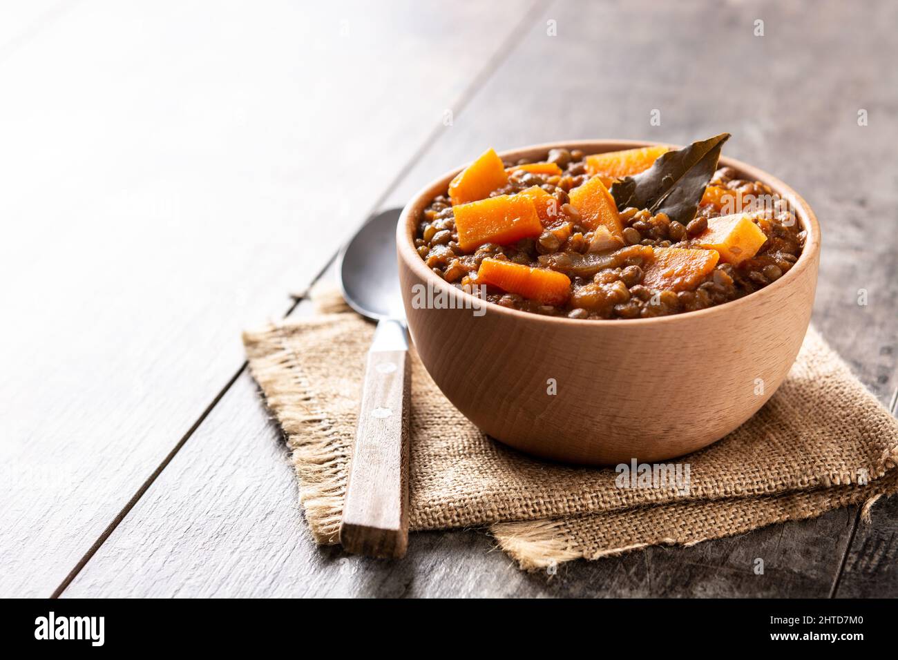 Lentil stew ragout with pumpkin and carrot in bowl on wooden table ...