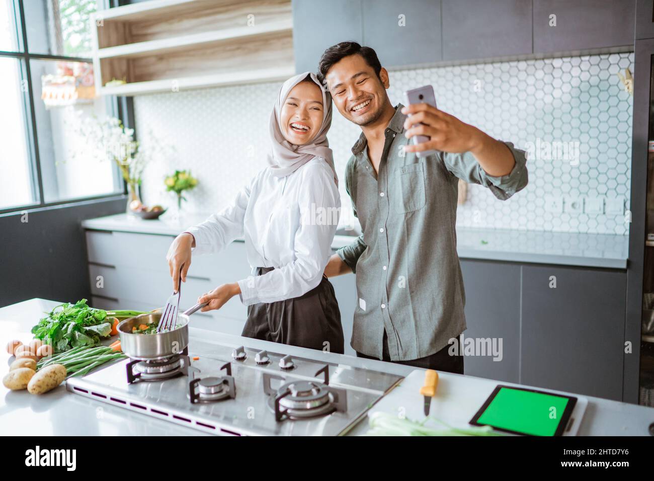 muslim couple cooking their food in the kitchen and taking selfie Stock ...