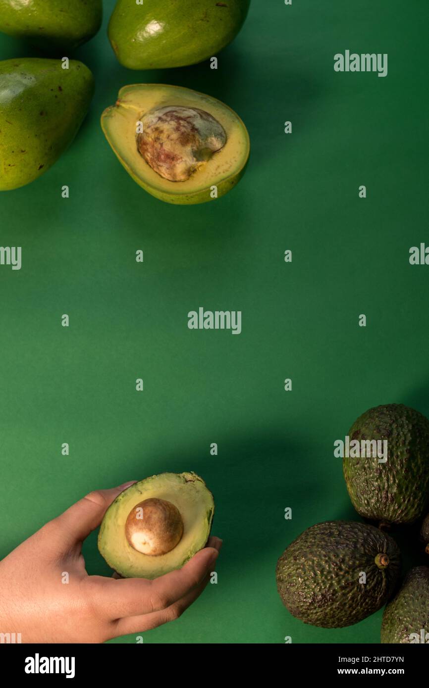 Vertical shot of avocados on the green background Stock Photo - Alamy