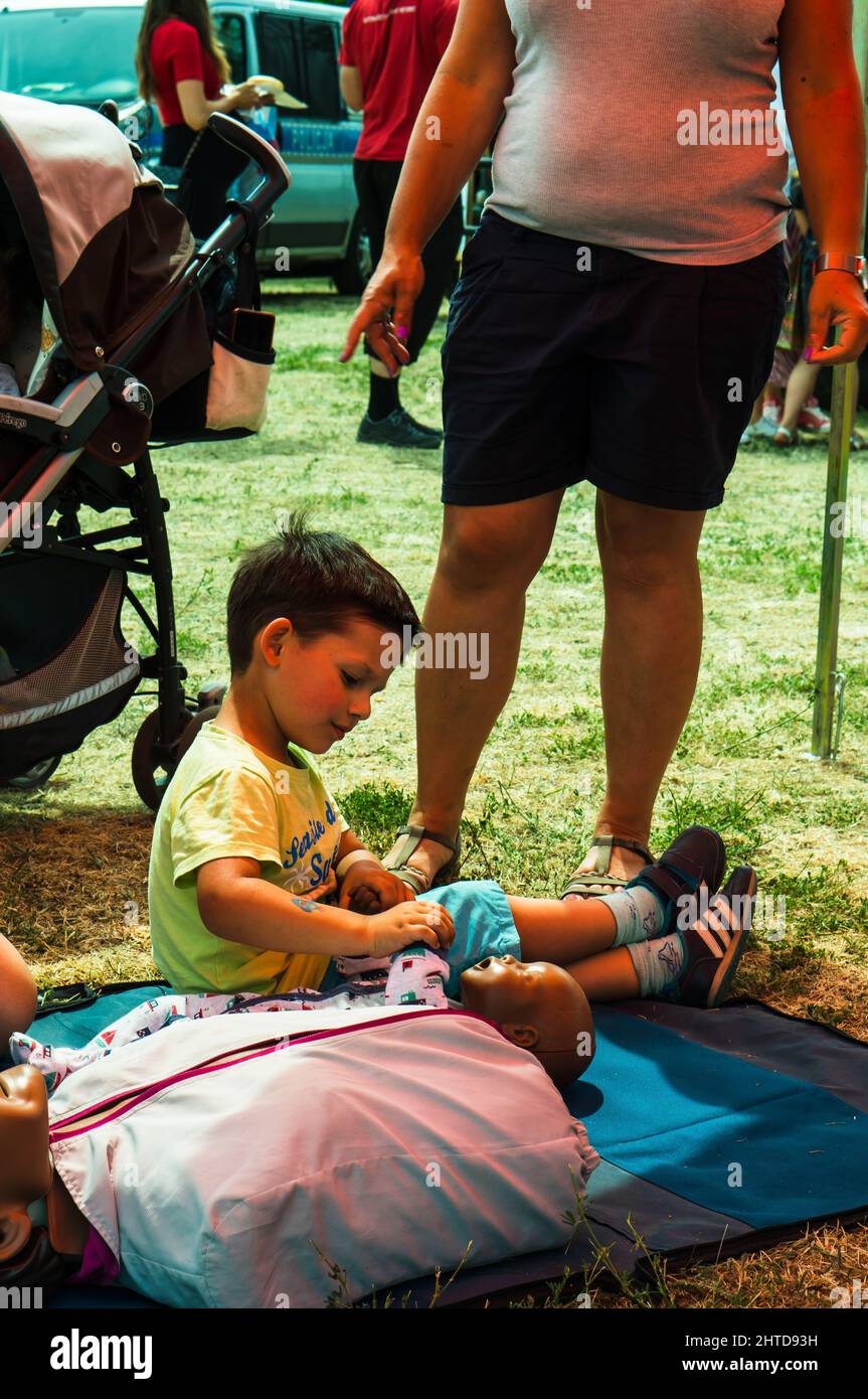 Young boy having first aid training on a baby doll during a fire ...