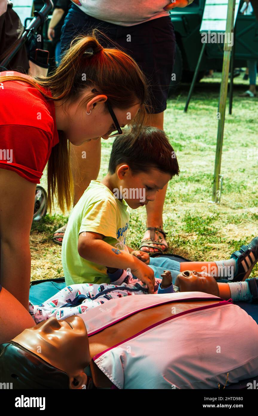 A young boy having first aid training on a baby doll during a fire ...