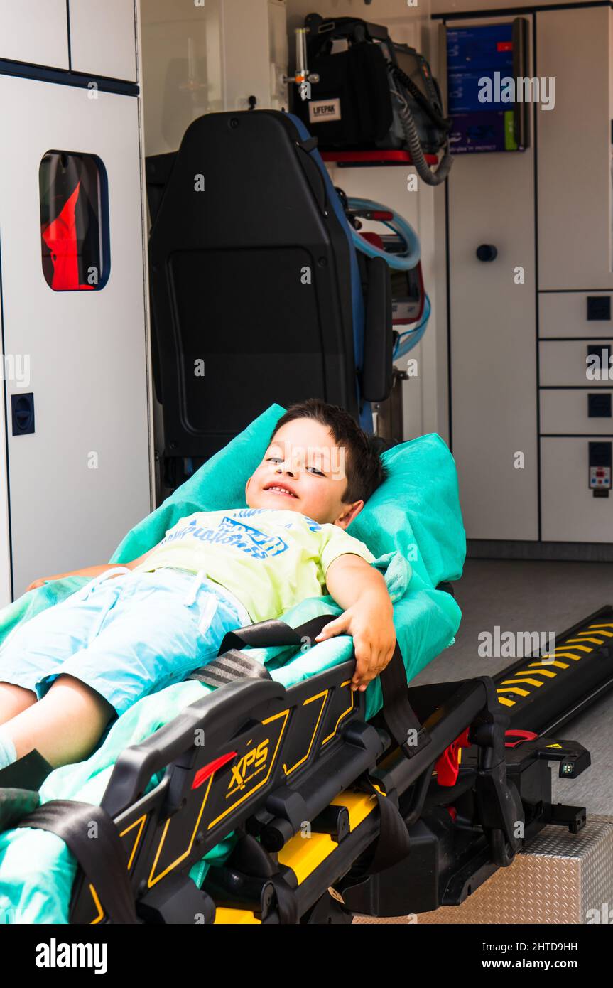 Young boy laying in a carrier of an ambulance during a fire department ...