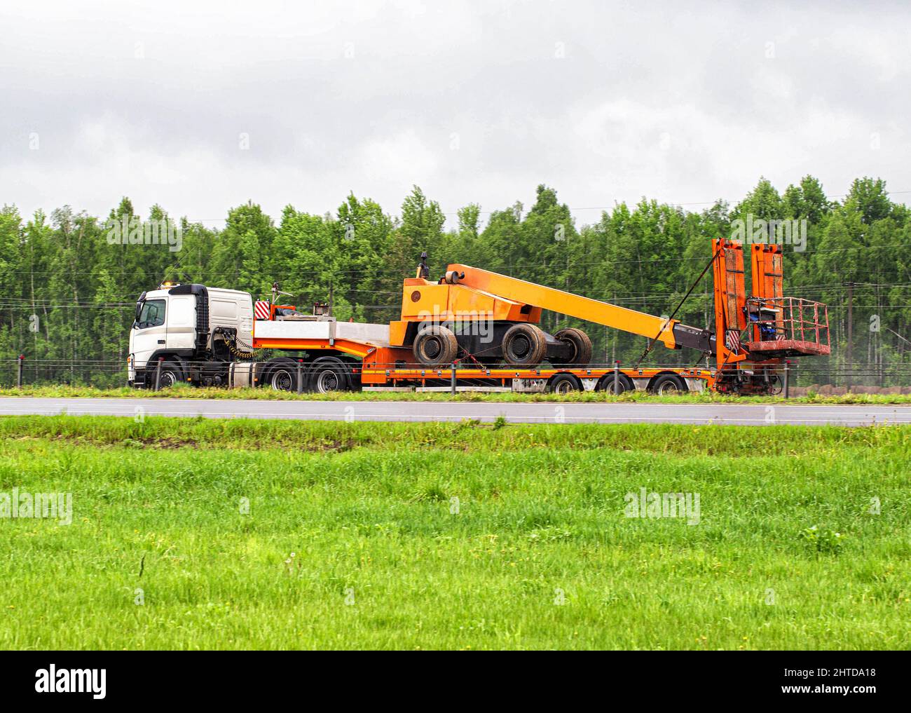 A truck with a trailer transports oversized cargo in the summer on the ...