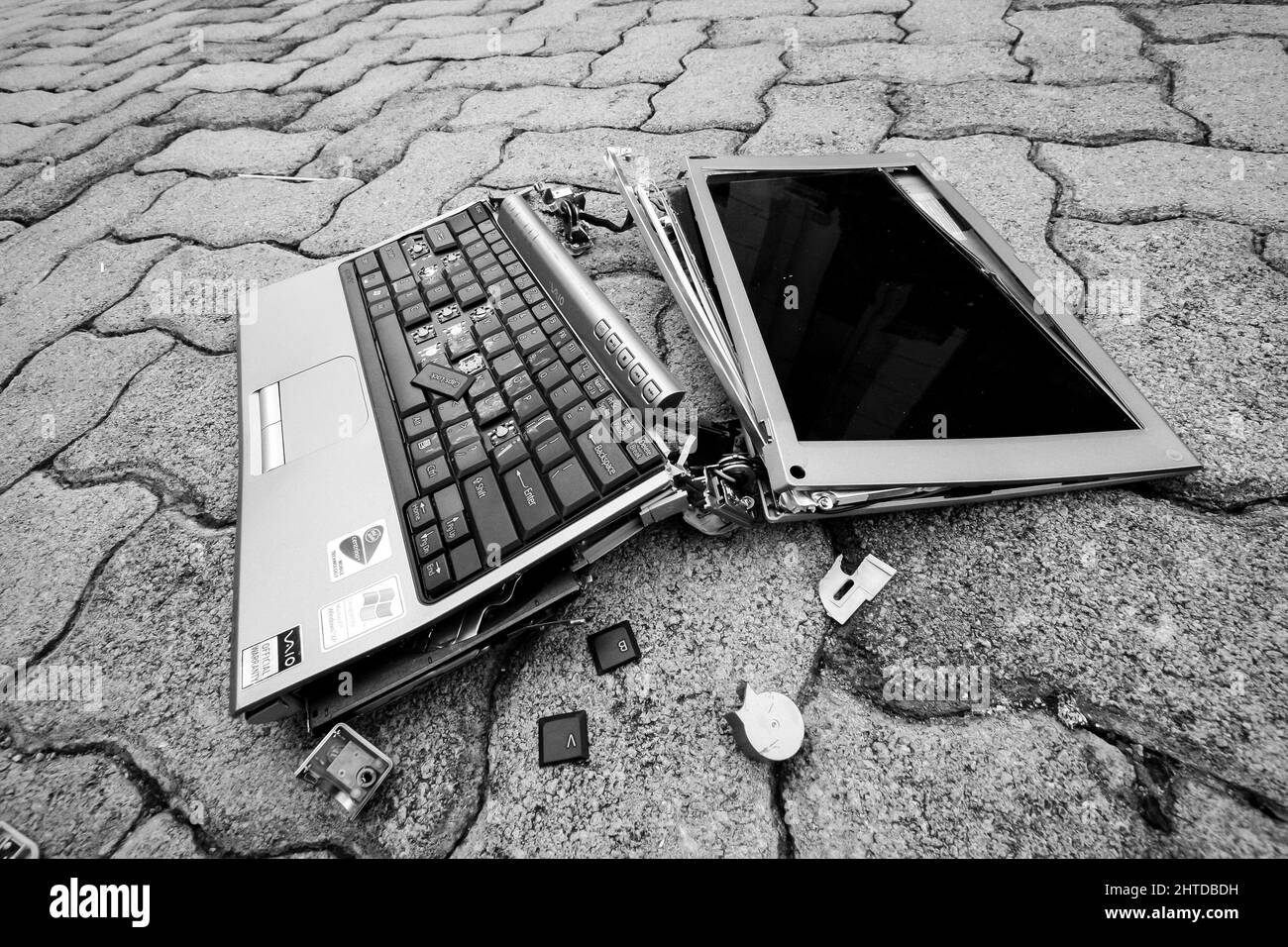Grayscale shot of a broken laptop computer on the brick pavement Stock ...